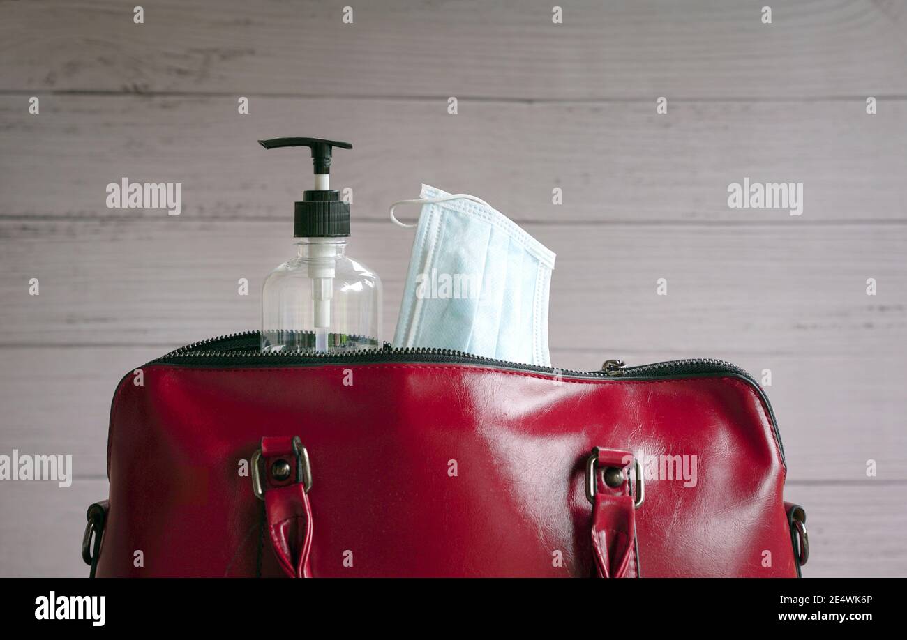 Face mask and hand sanitizer inside woman red handbag. Health and ...