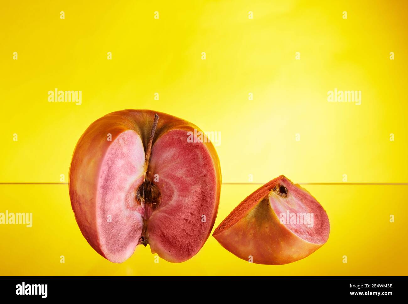 An apple with red flesh inside the cut wedge lies nearby. Yellow ...