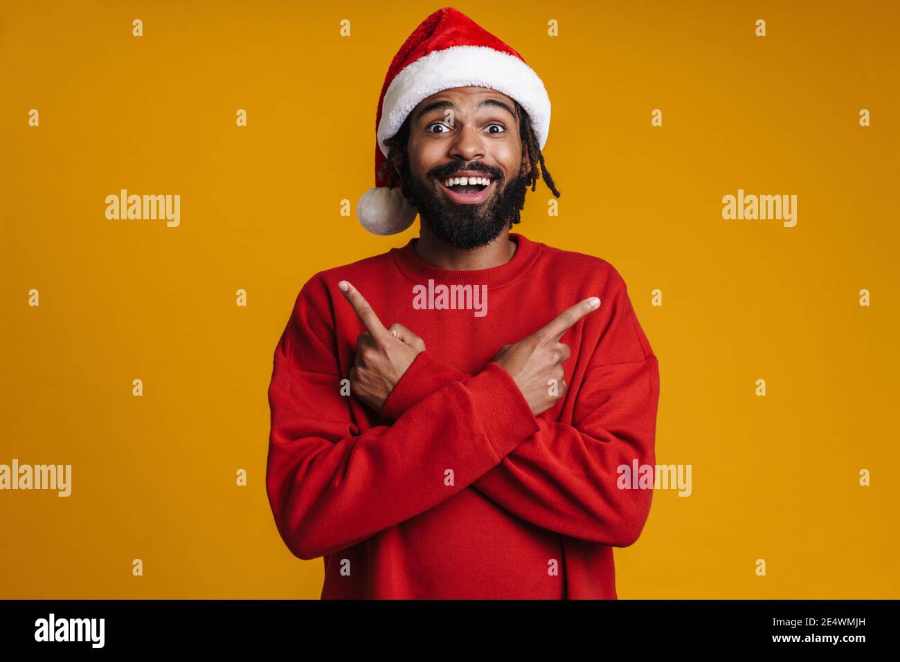 Joyful african american guy in Santa Claus hat pointing finger at ...