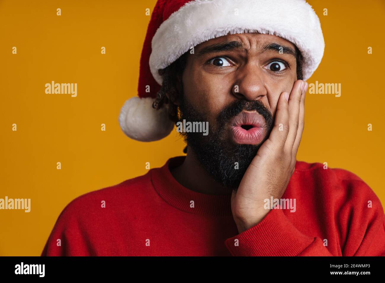 Shocked african american guy in Santa Claus hat posing and looking at ...