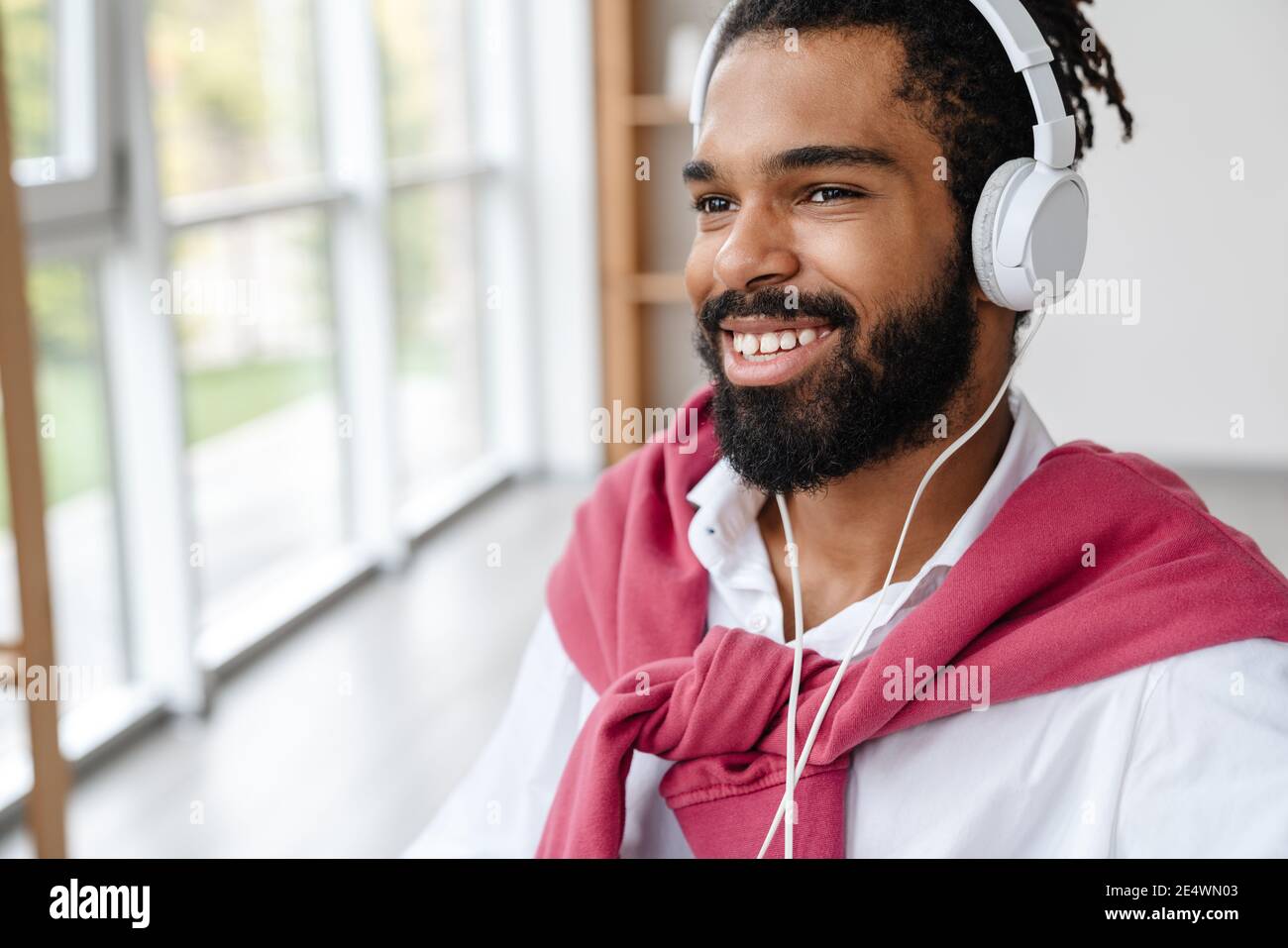 Cheerful african american guy smiling and listening music with ...