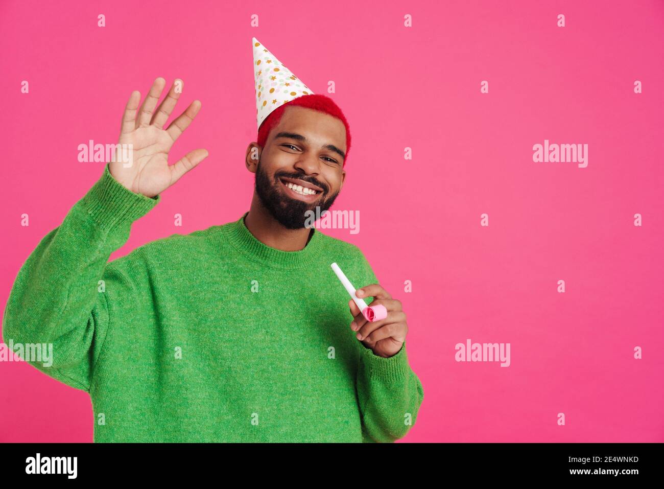 Cheerful african american guy waving hand and holding party whistle ...