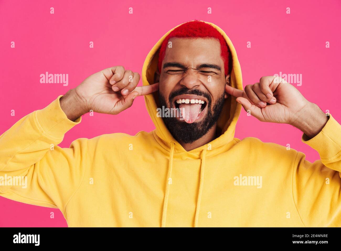 Amusing african american guy showing his tongue and plugging his ears ...