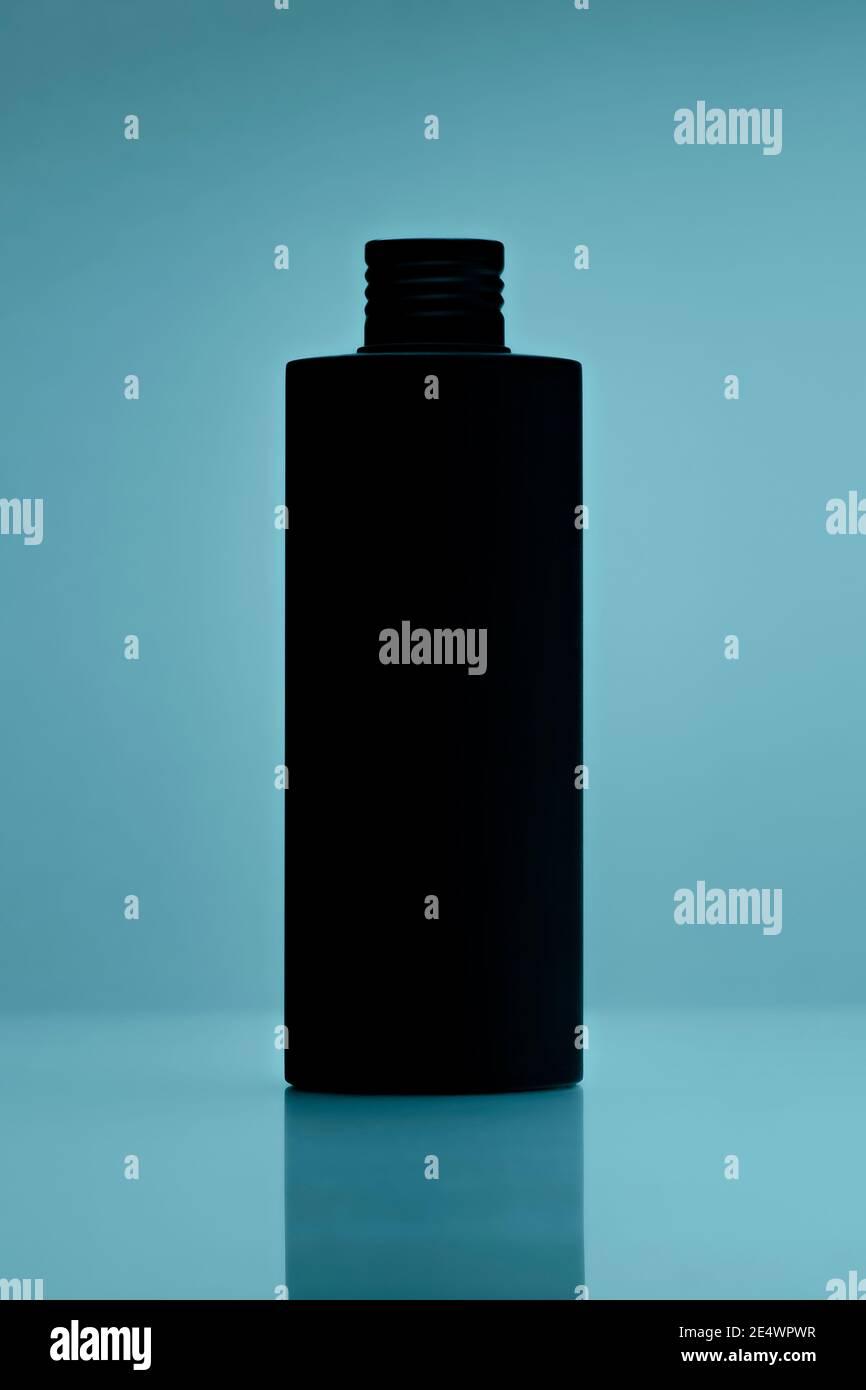 close up of a black unbranded bottle on tile blue background. cosmetic ...