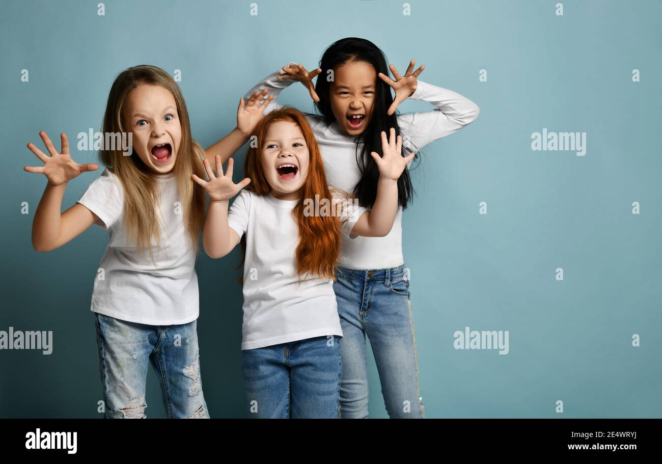 Playful multiracial girls friends in jeans and white t-shirts standing ...