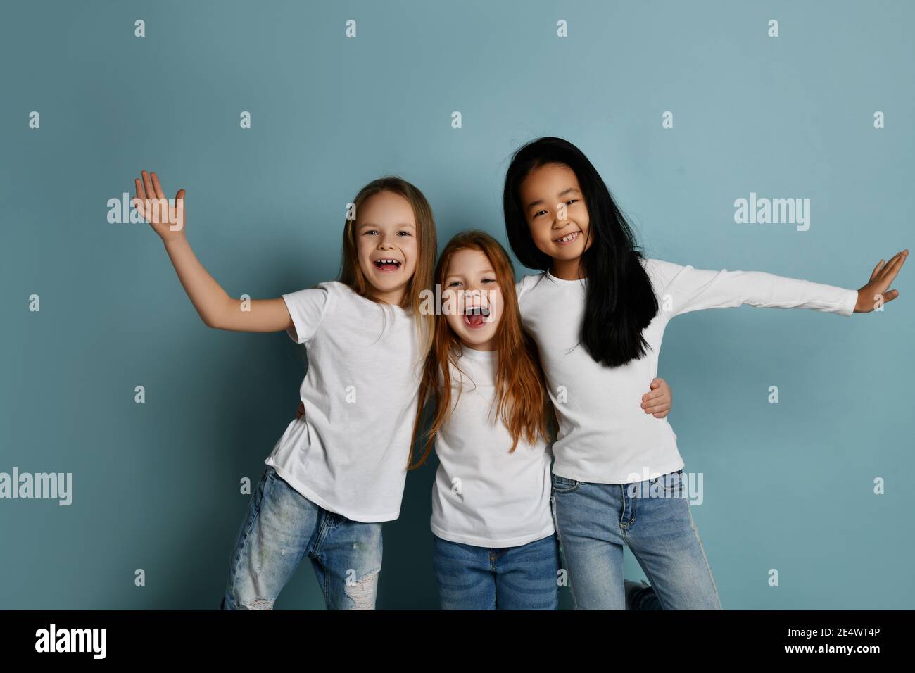 Cheerful multiracial girls friends in jeans and white t-shirts have fun ...