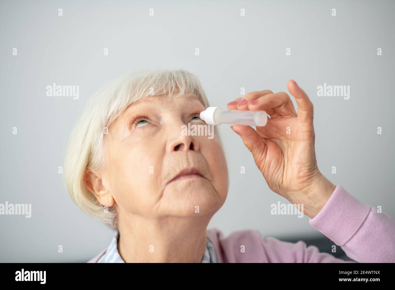 Senior woman dropping eyedrops into her eye Stock Photo - Alamy