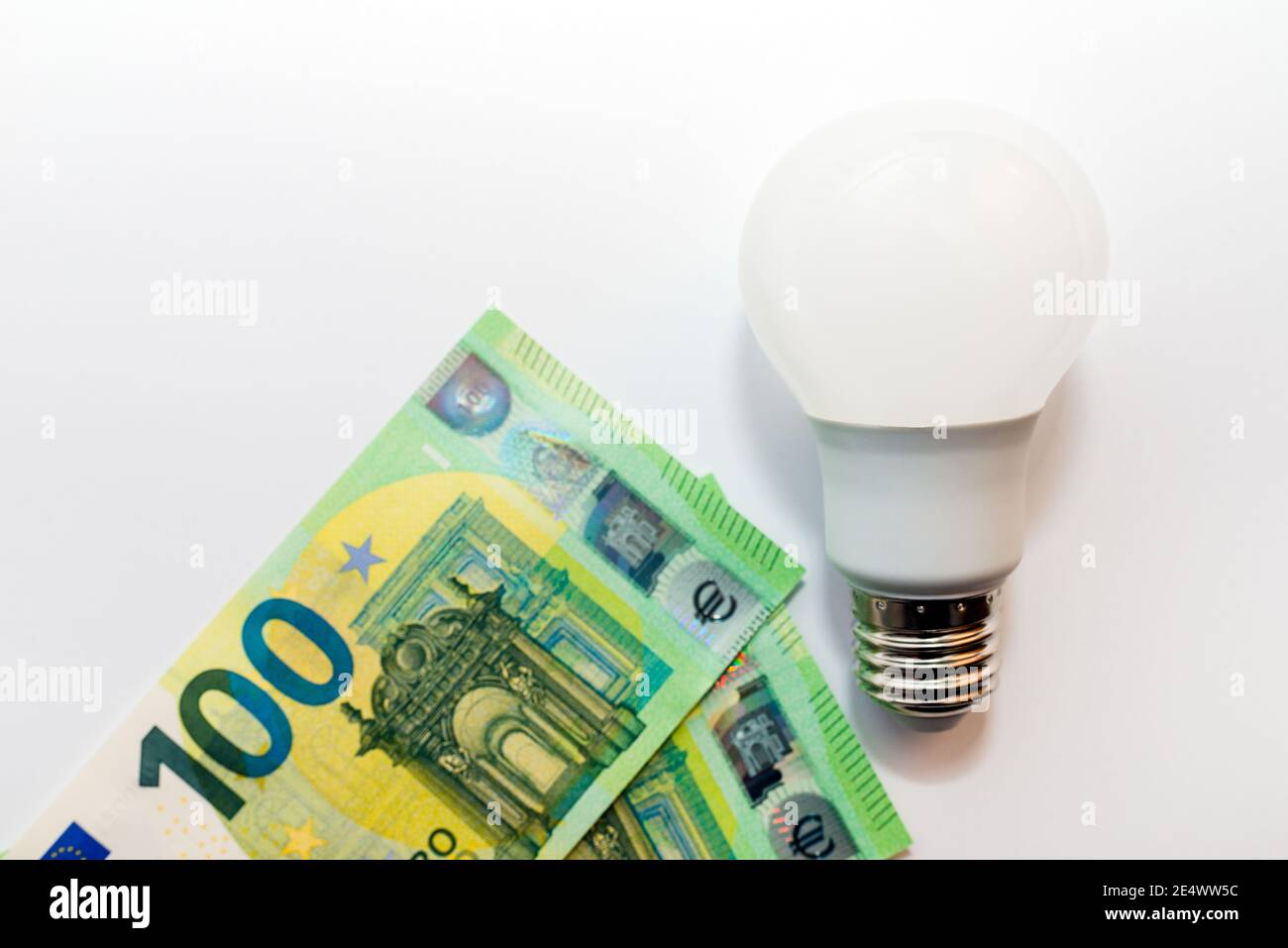 One LED bulb and 100 euro bills on white light background Stock Photo ...