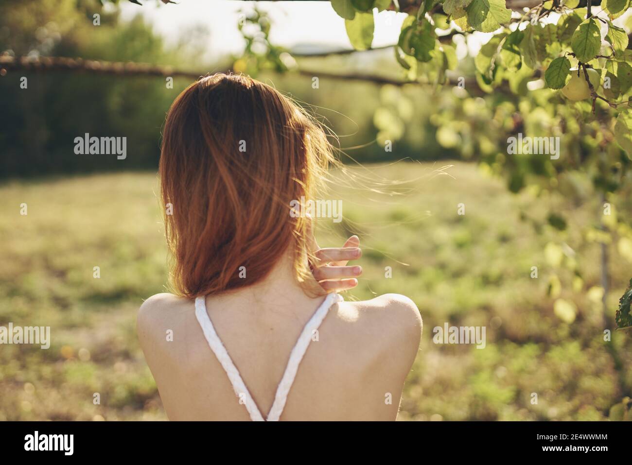 attractive woman in a sundress near trees in the garden in summer back ...