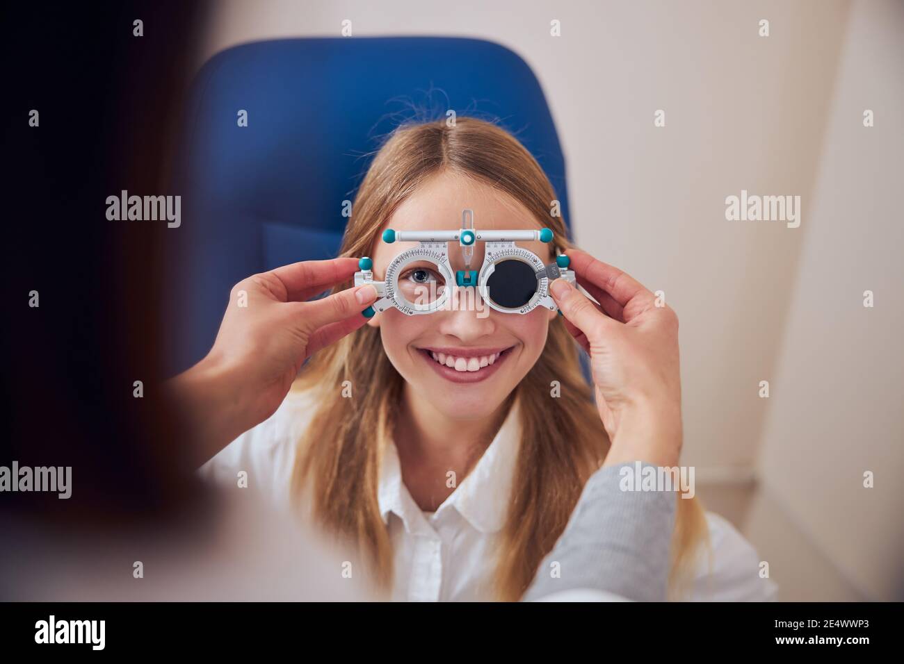 Cute girl looking at the photo camera while checking eyesight in doctor ...