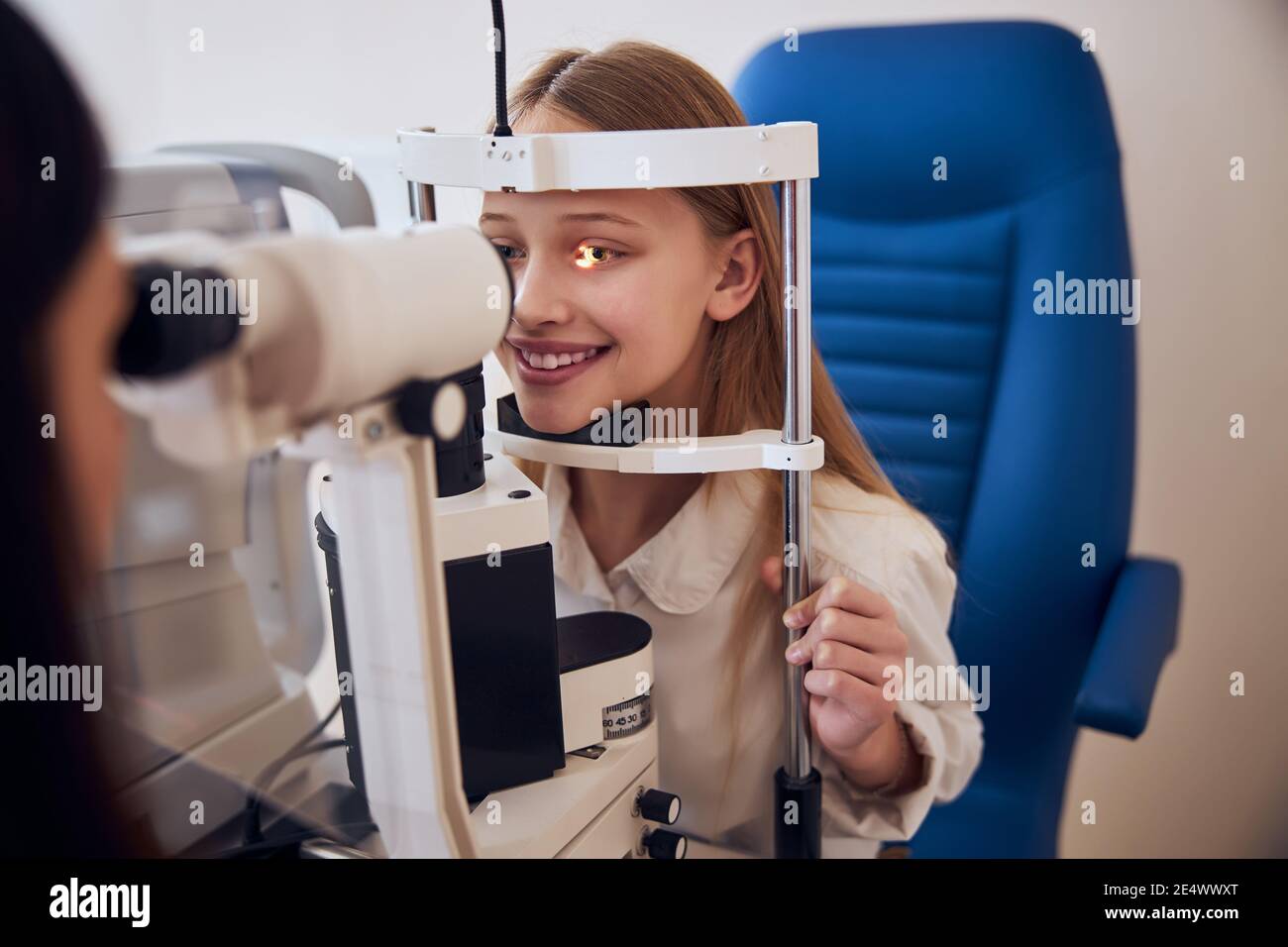 Beautiful teenager girl talking with doctor optician while they ...