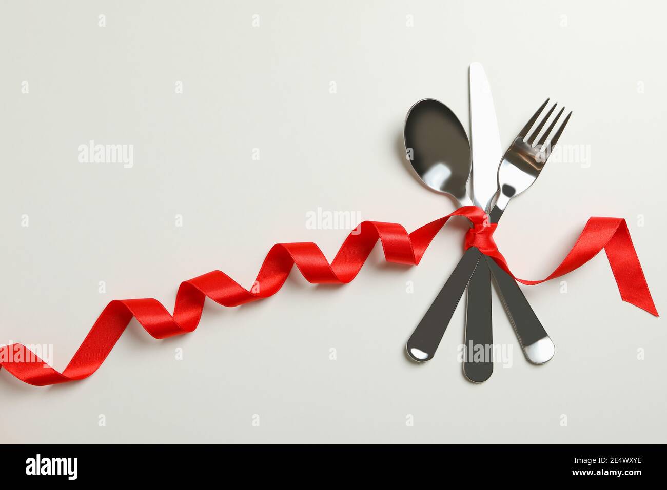 Cutlery with red ribbon on white background Stock Photo - Alamy
