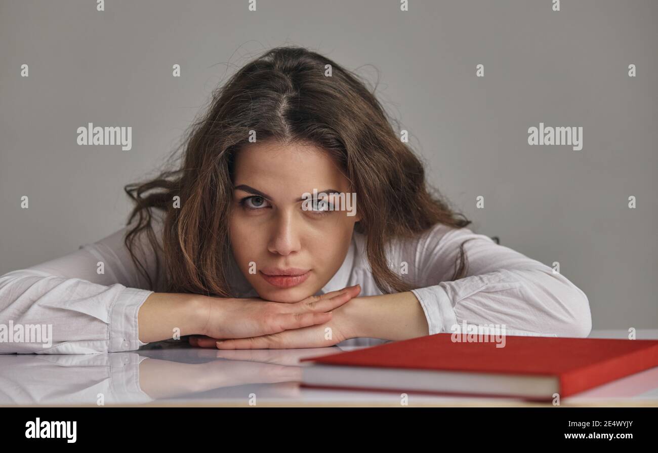 Tired bored teen girl upset by difficult learning looking at books ...