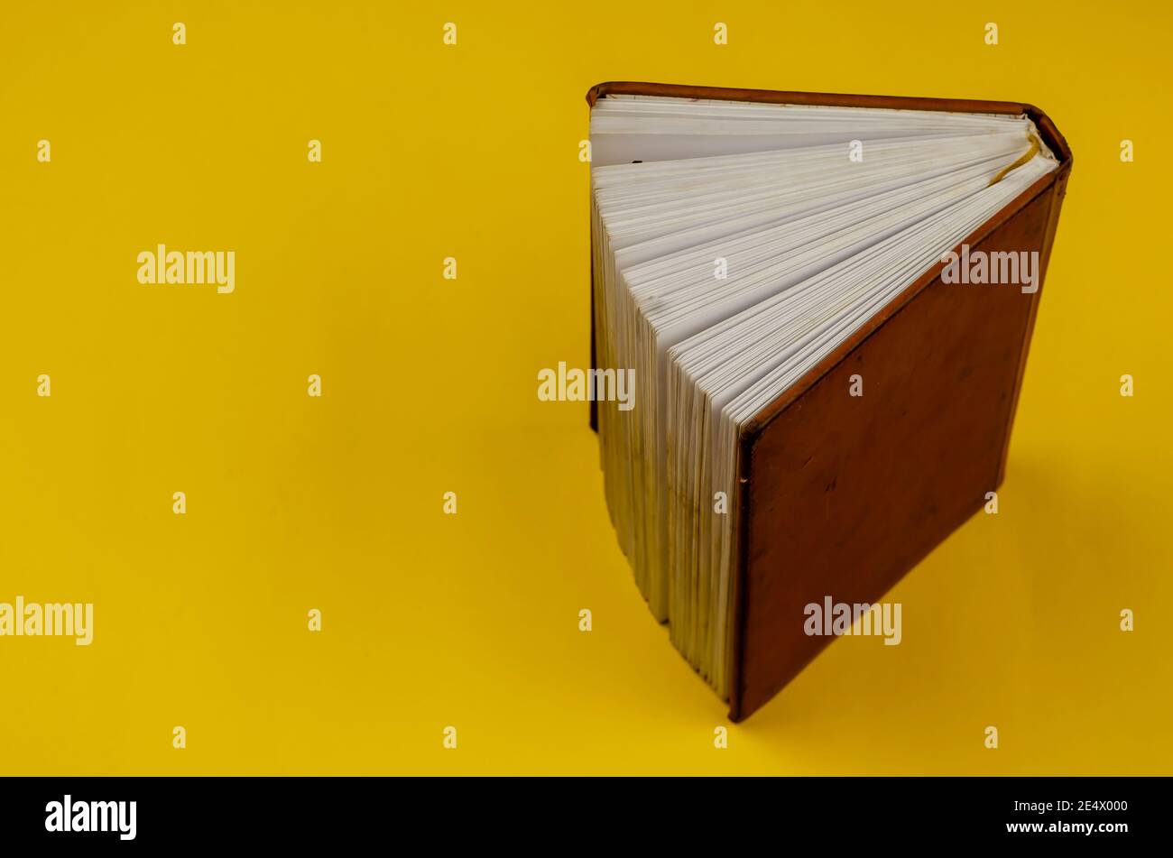Old diary in brown leather binding stands on endpaper on yellow ...