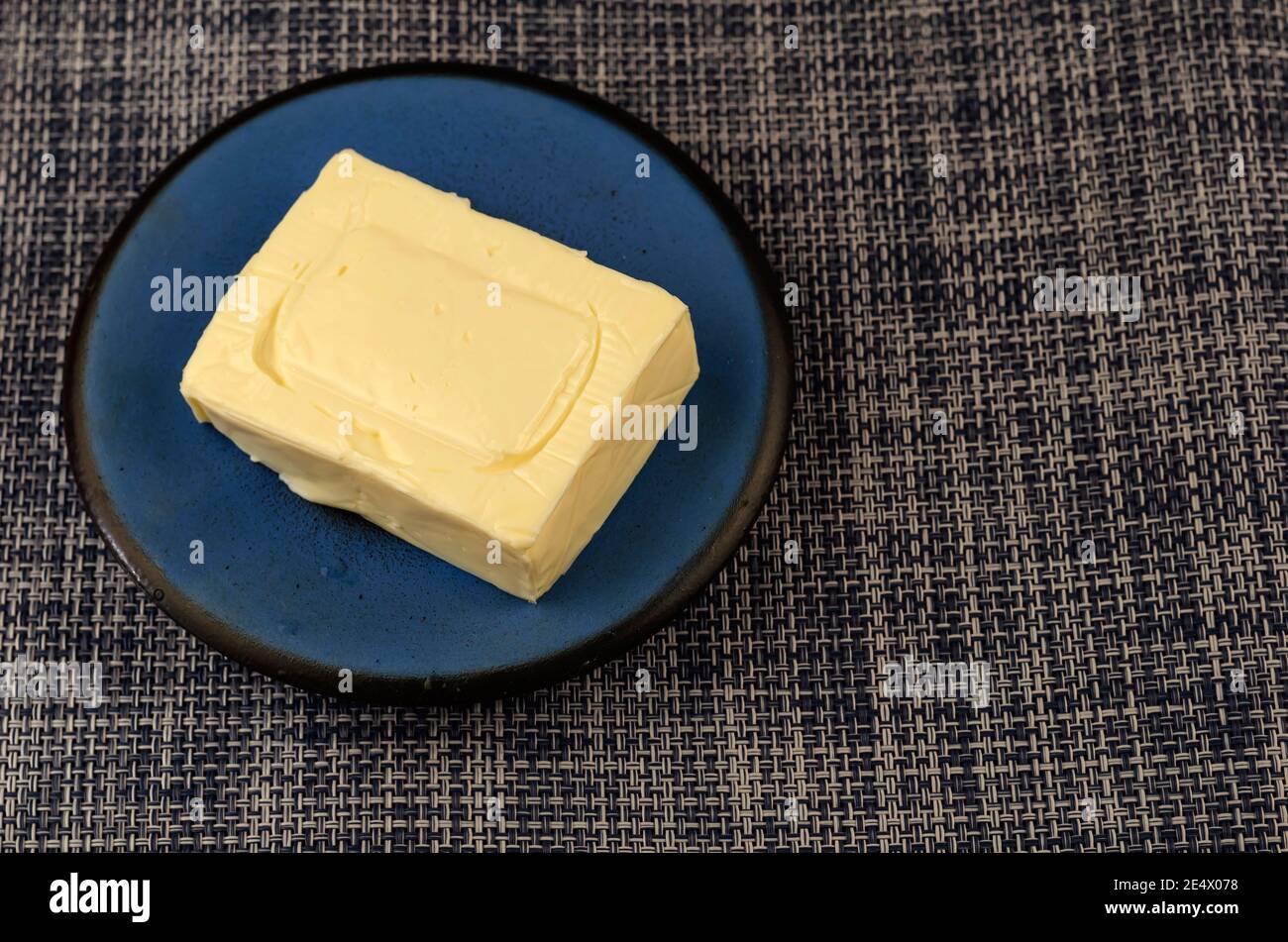 Rectangular slice of processed cheese in a blue saucer on a denim ...