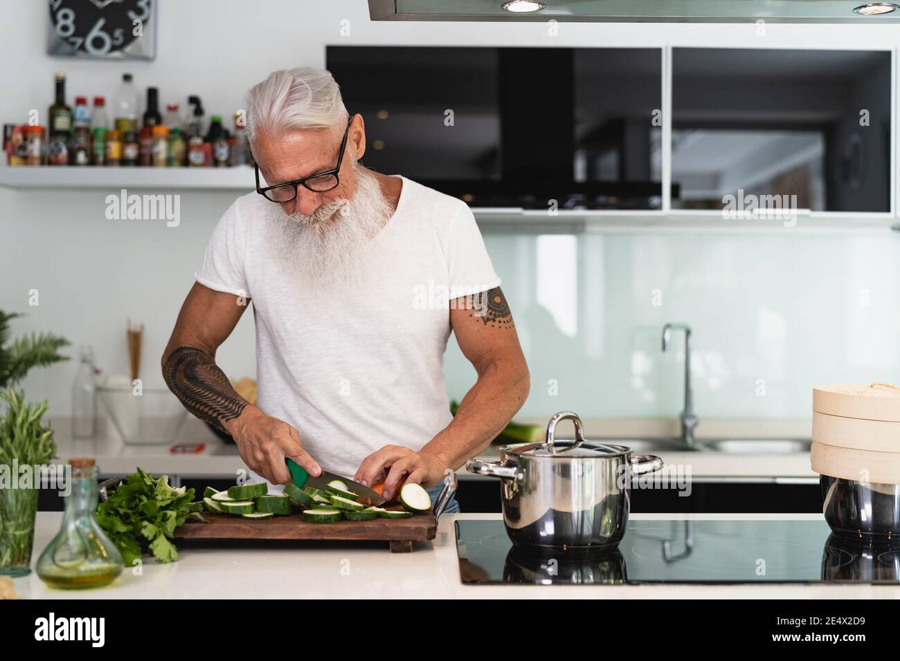 Happy senior man having fun cooking at home - Elderly person preparing ...