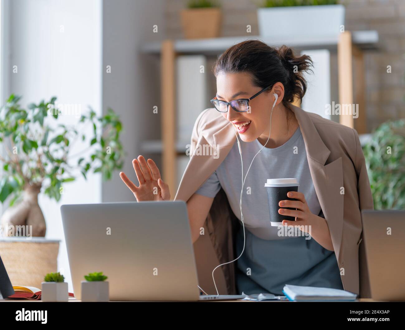 Happy casual beautiful woman working on a laptop, talking with somebody ...