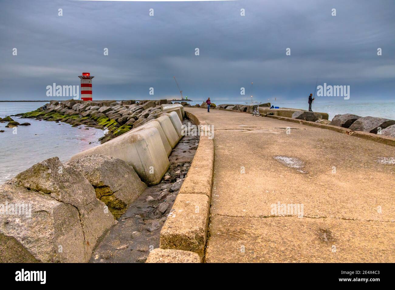 Concrete jetty near IJmuiden with angler fishermen on a cloudy ...
