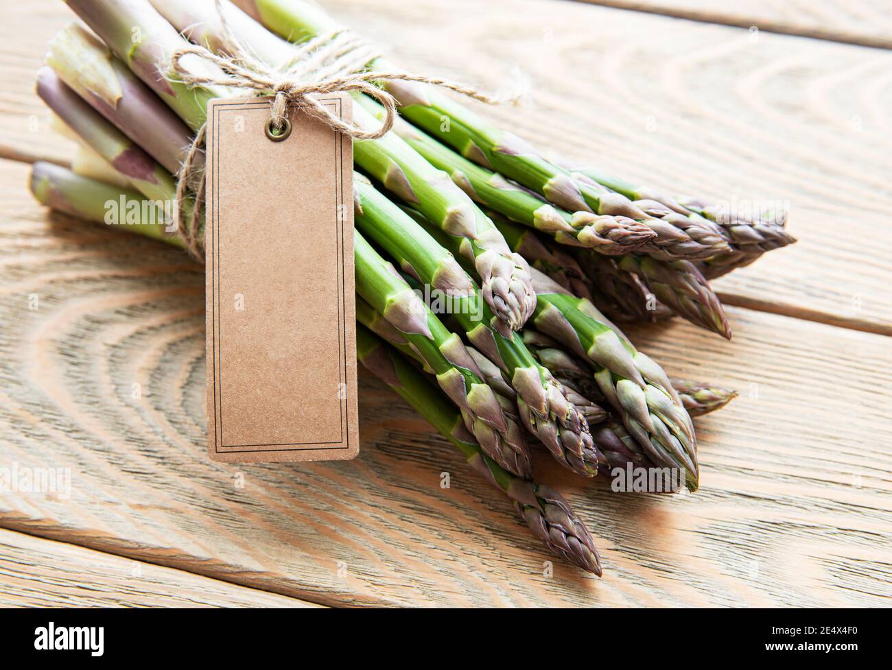 Fresh green asparagus with empty tag on old wooden table. Flat lay ...