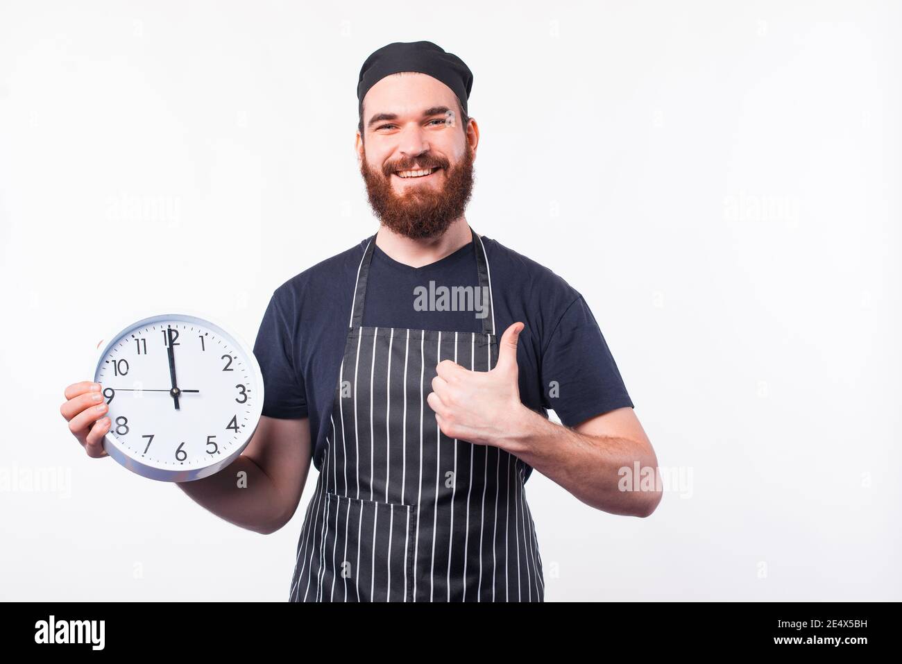 Photo of happy chef man holding wall clock and showing thumb up Stock ...