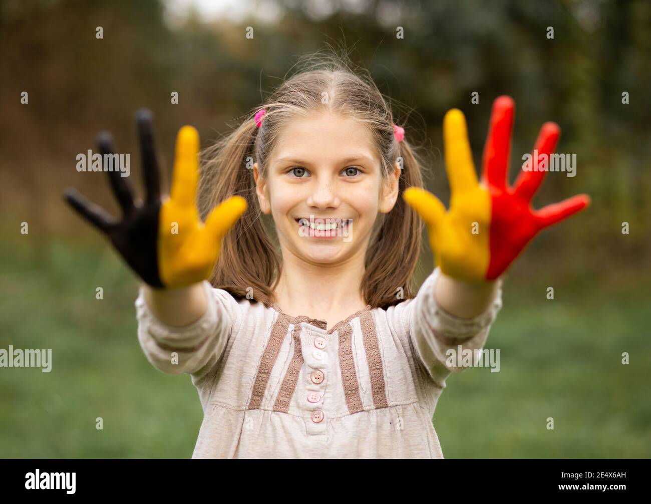Happy outdoor portrait of child girl with hands painted in Belgium flag ...
