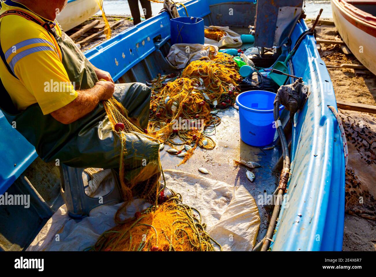 Fisher in rubber trousers and boot is sitting in his boat and pile up ...