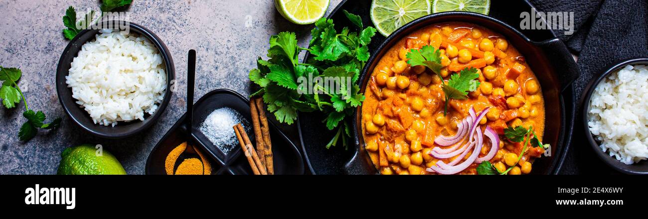 Vegan chickpea curry with rice and cilantro in a black bowl, dark ...