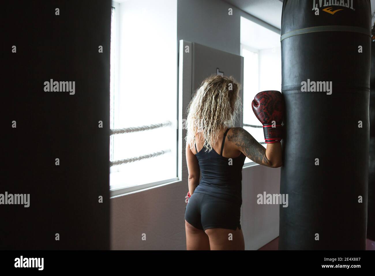 A woman with long curly blonde hair with a boxing glove near a punching ...