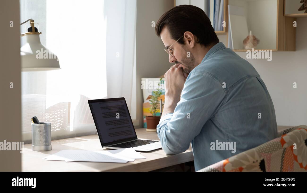 Focused young man author creating story using laptop app Stock Photo ...