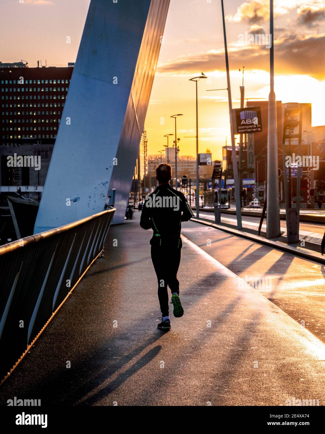 ROTTERDAM, NETHERLANDS - Nov 30, 2019: Someone jogging during sunrise ...