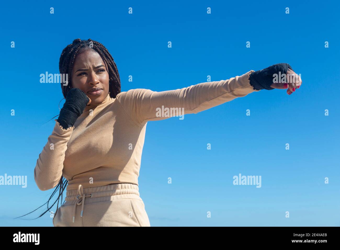 Young afro black girl training martial arts, boxing outdoors with sea ...