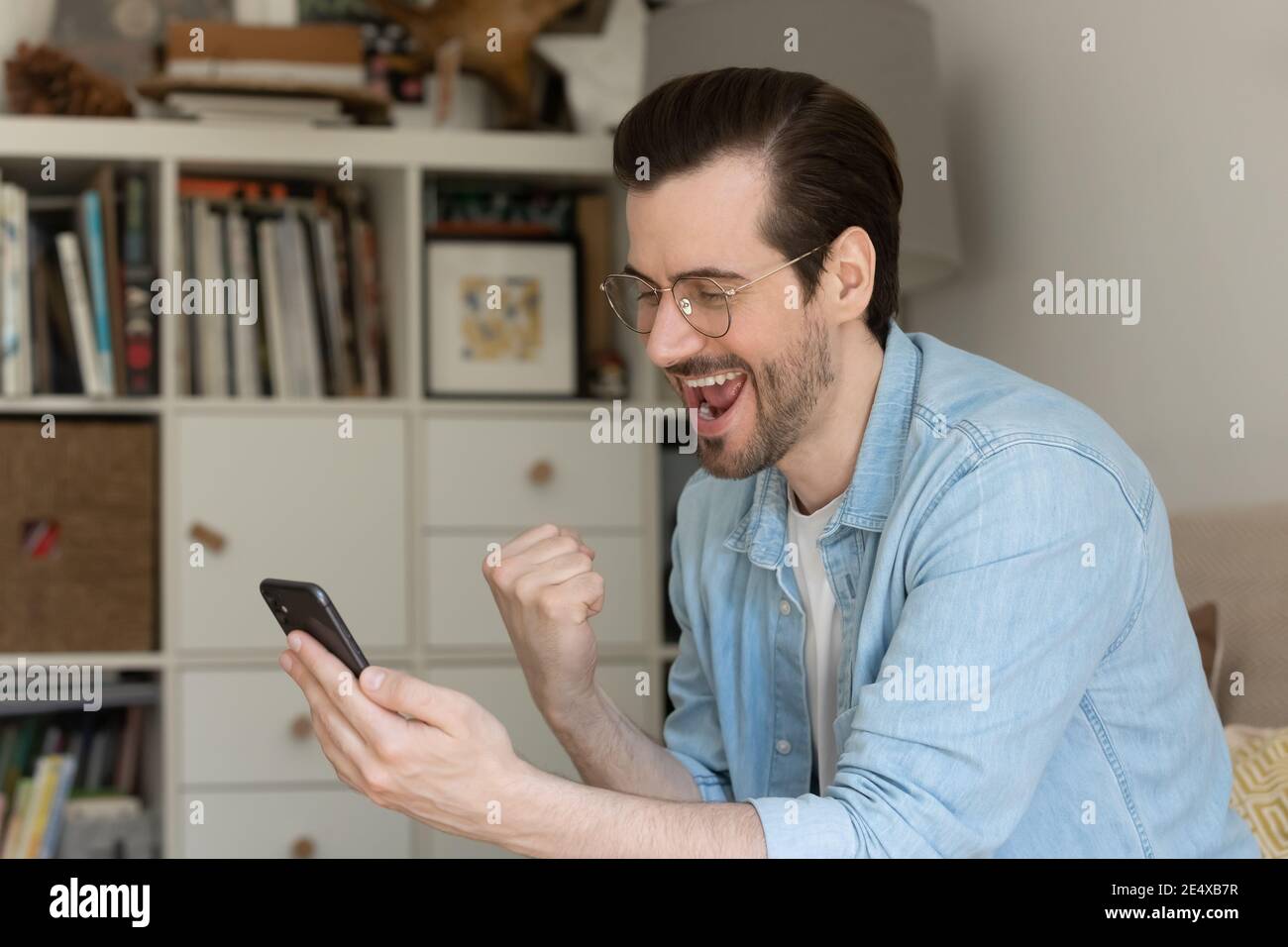 Laughing man screaming yes reading good message from phone screen Stock ...