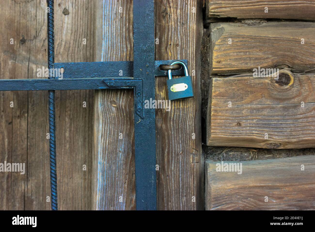 Wooden brown door protected by a black metal lattice and a secure lock ...