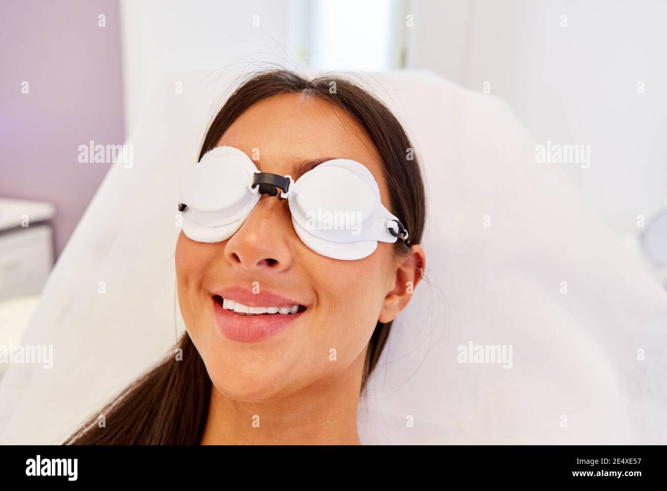 Young patient with protective goggles before a skin treatment with the ...