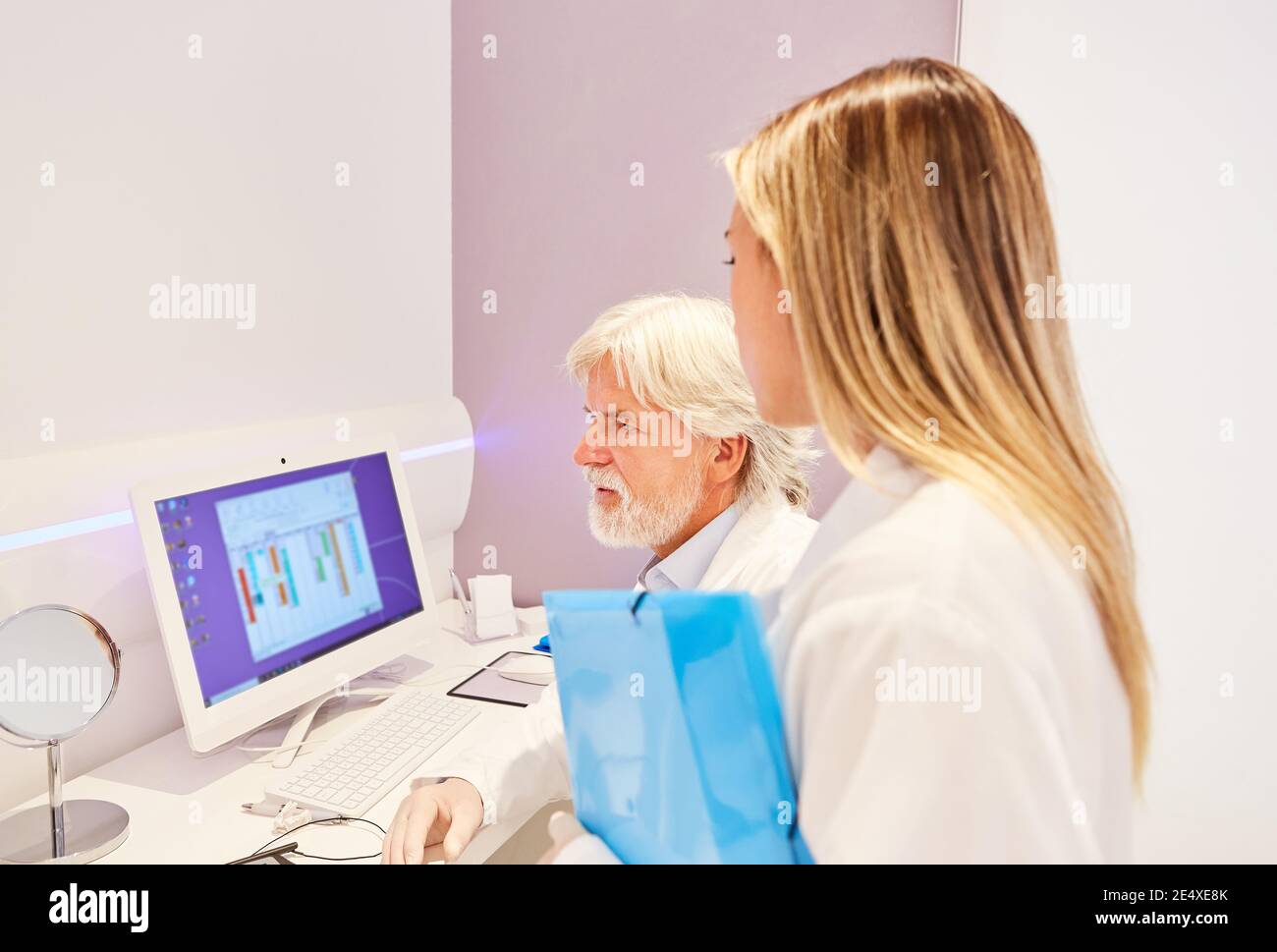 Family doctor and medical assistant together on the computer monitor in ...