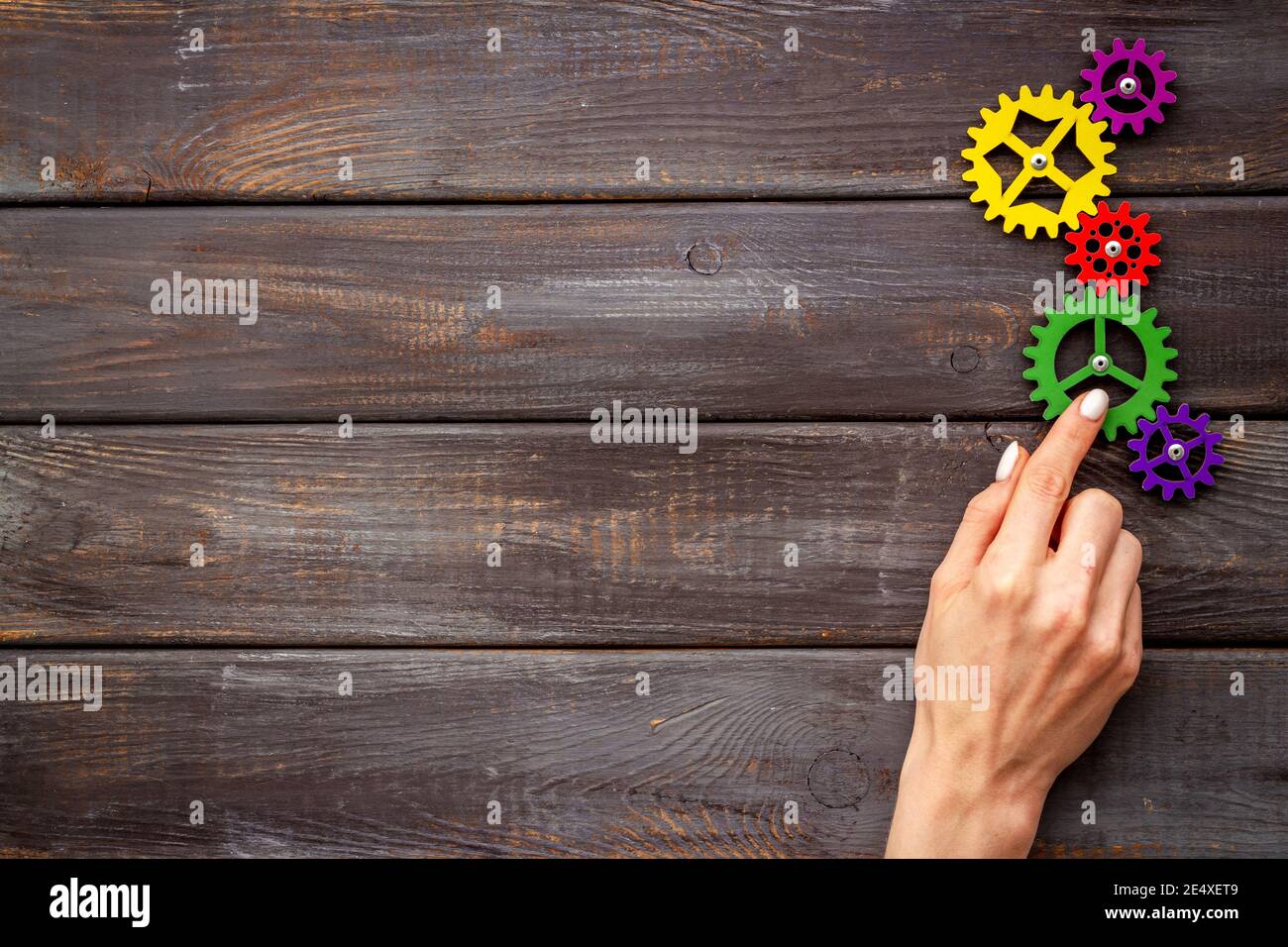 Hand puts a gear into one working mechanism. Teamwork and collaboration ...