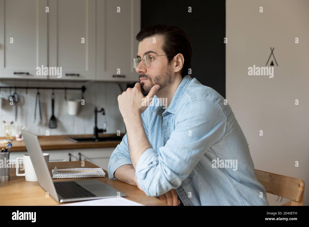 Pensive young male student pondering on task on distance learning Stock ...