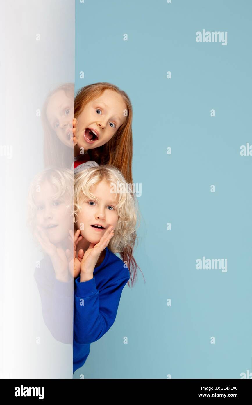 Astonished. Happy children isolated on blue studio background. Look ...