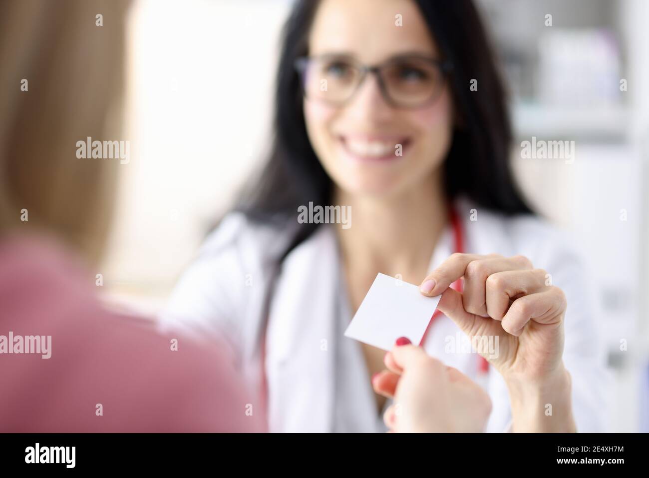 Doctor hands over business card to patient in office Stock Photo - Alamy