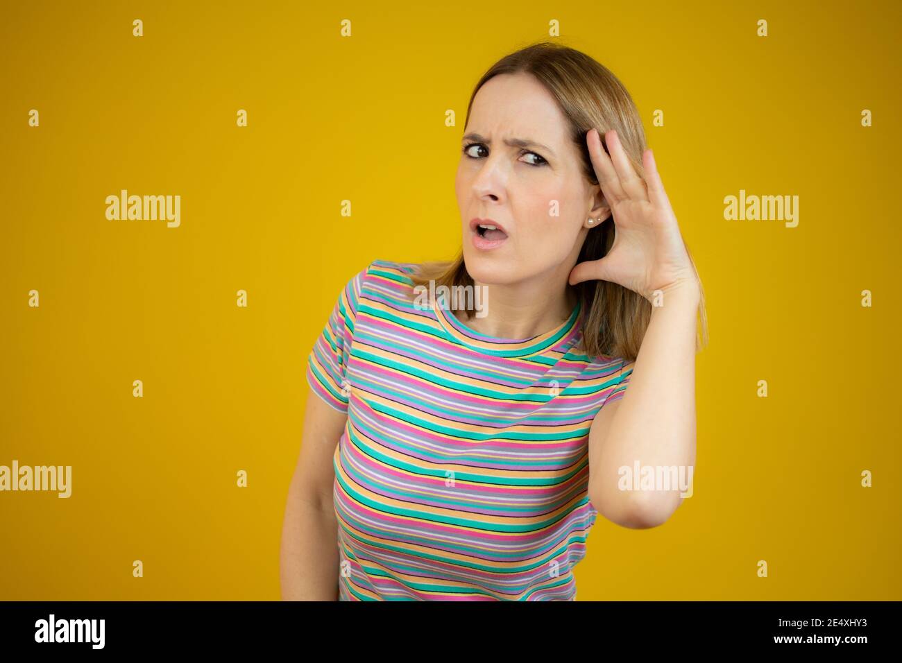 Young woman over isolated yellow background listening to something by ...