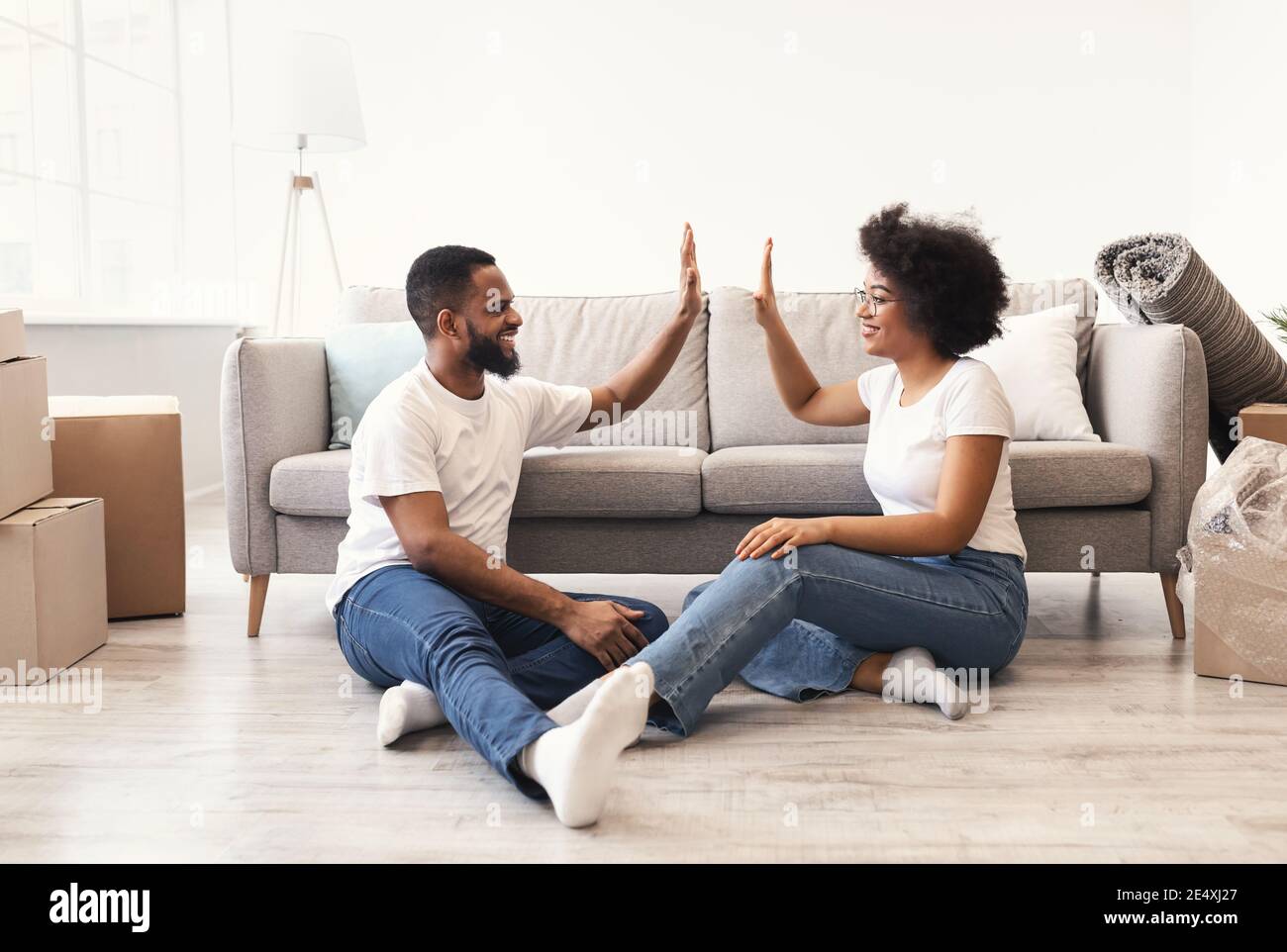 Couple Celebrating Moving House, Giving High-Five Sitting Among Boxes ...