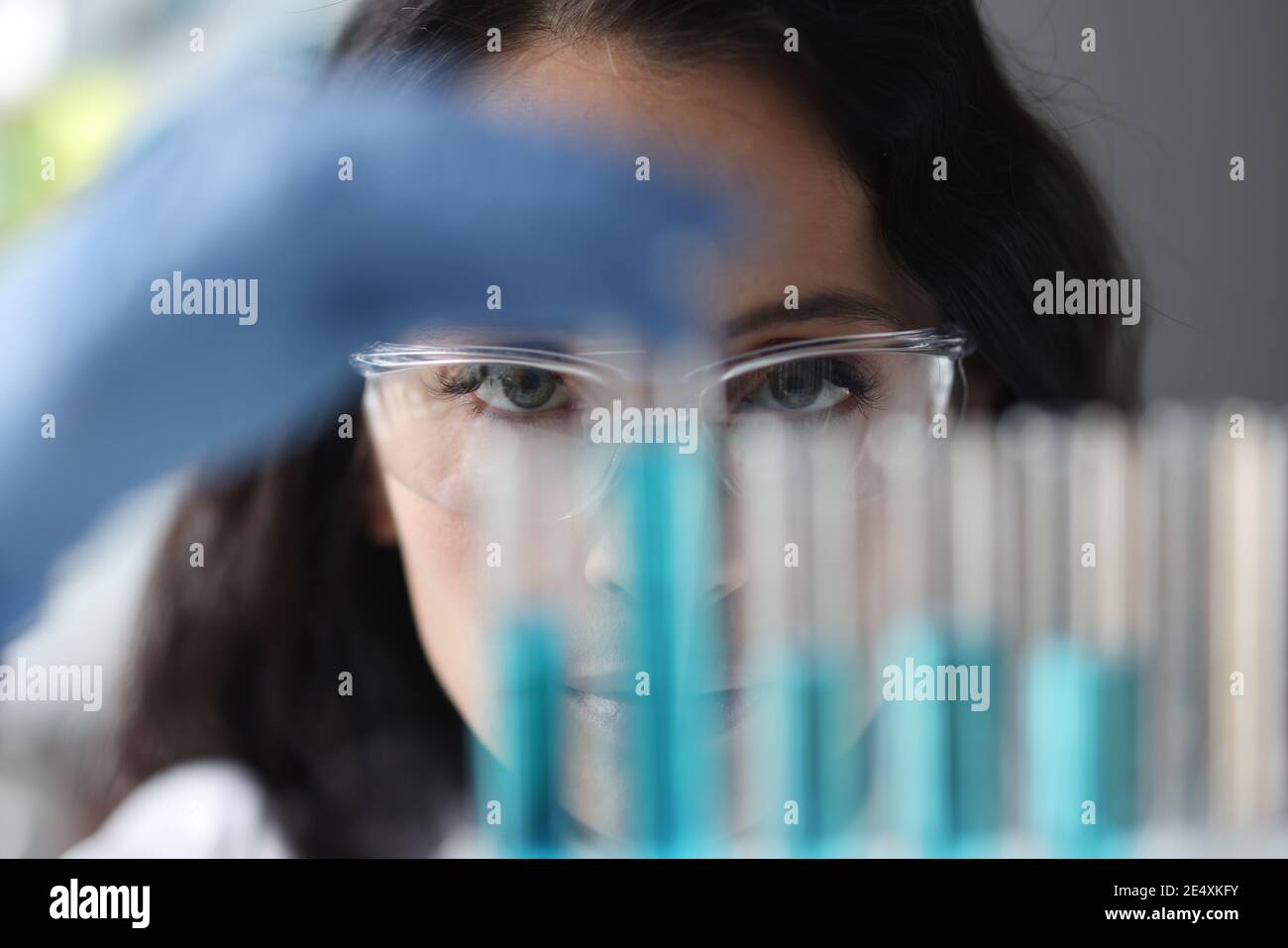Portrait of woman in glasses who looks at test tubes with liquid Stock ...