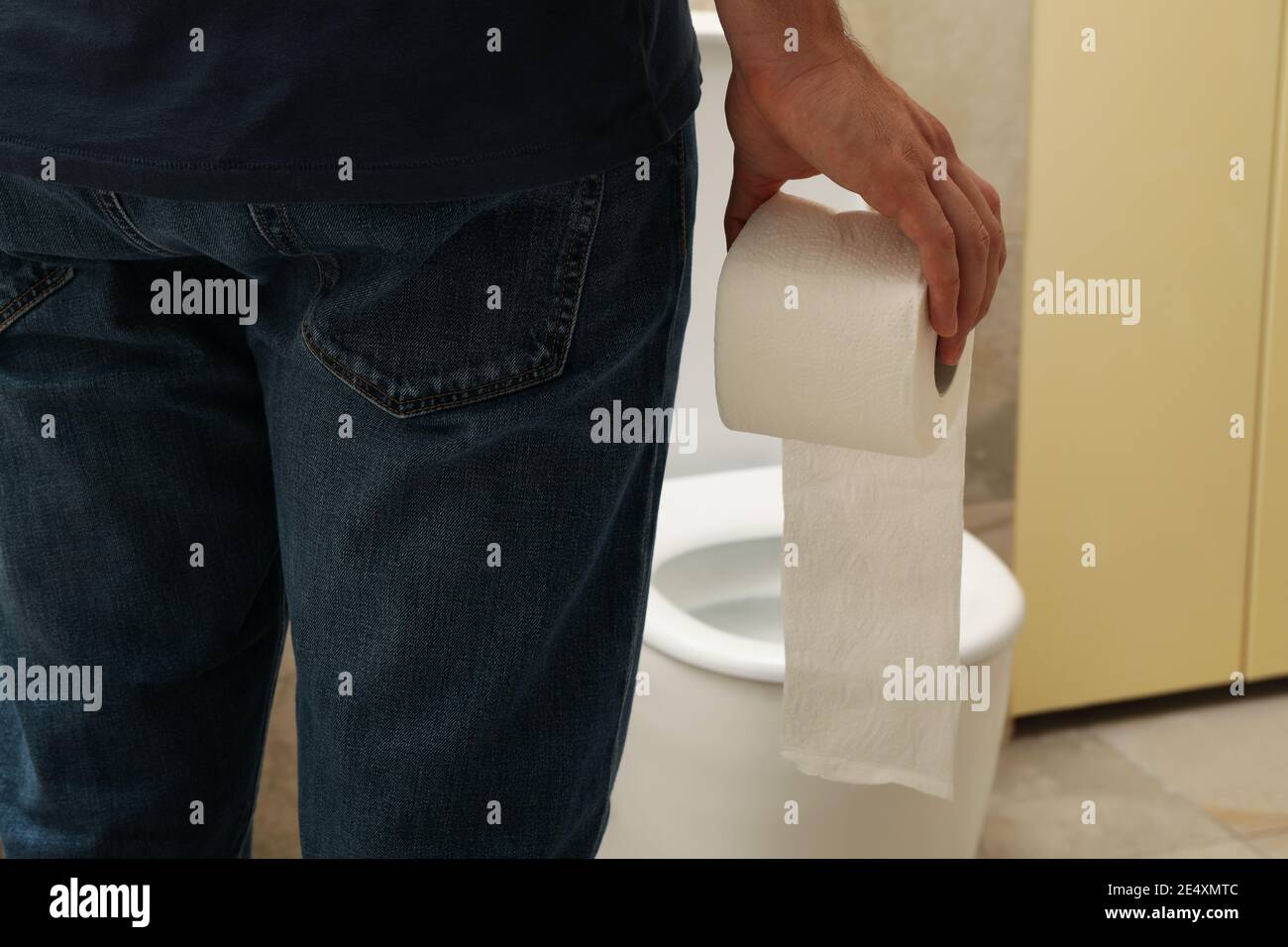 A man stands near the toilet and holds toilet paper Stock Photo - Alamy