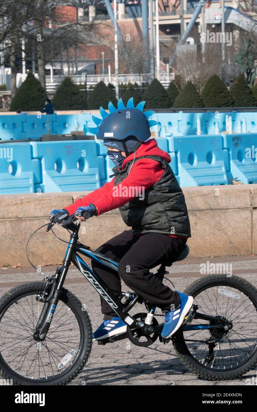 A young lad with an ornate Mohawk styled bike helmet peddles around the ...
