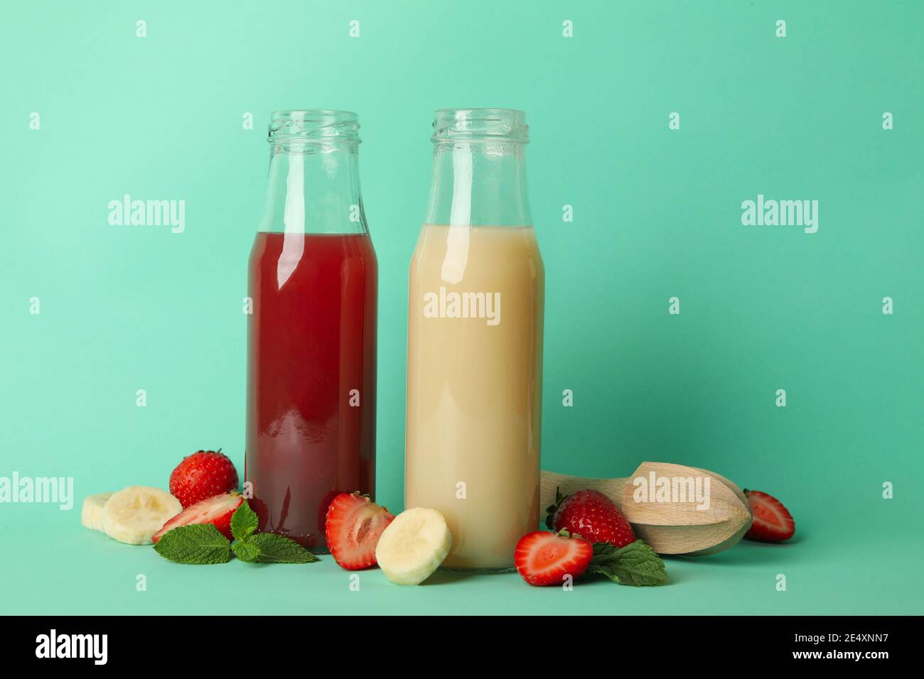 Bottles with strawberry and banana juices on mint background Stock ...