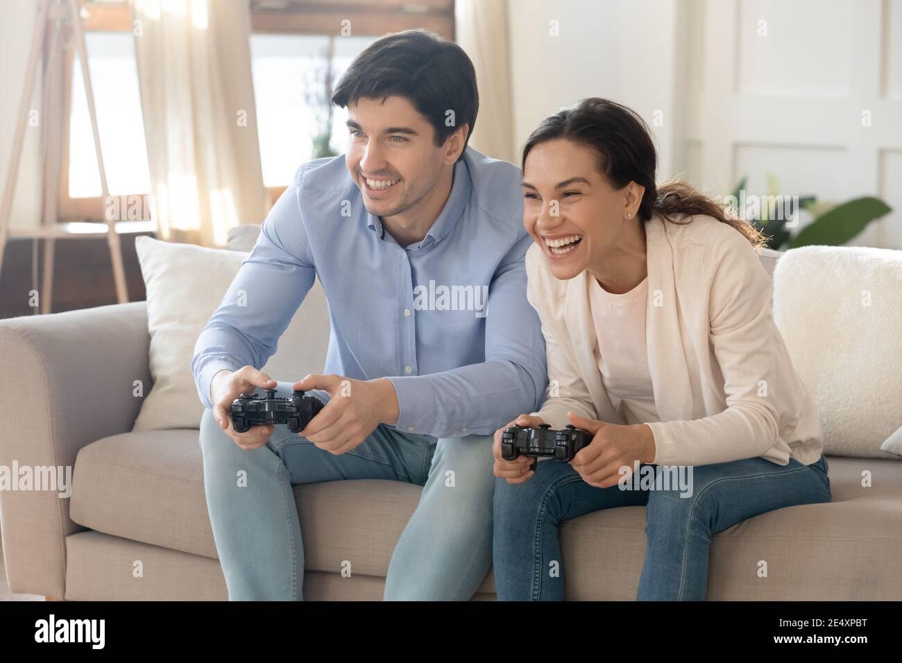 Overjoyed young couple playing video game, holding remote controllers ...