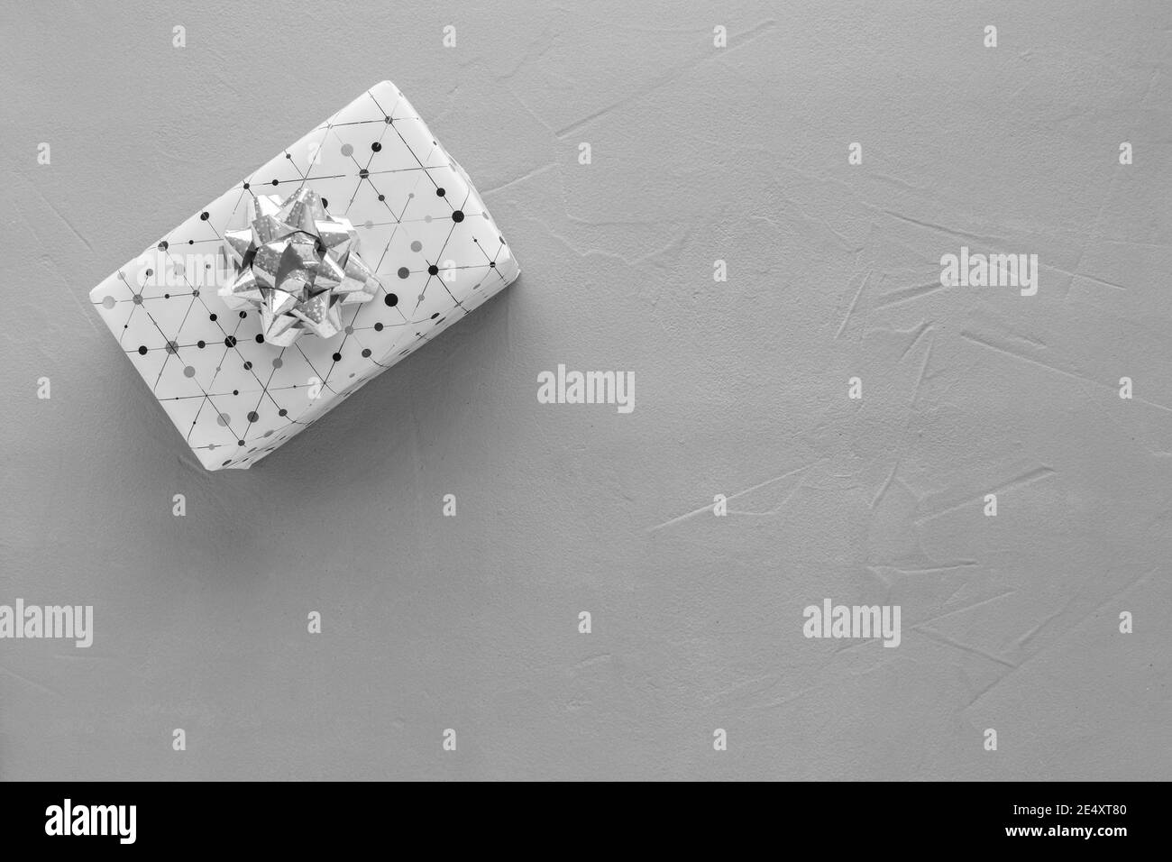 Gift box in a beautiful wrapper with a bow on a gray concrete ...