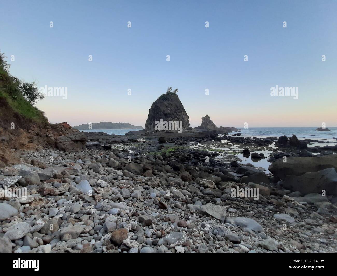 one single rock hill surrounded from stones and waves Stock Photo - Alamy