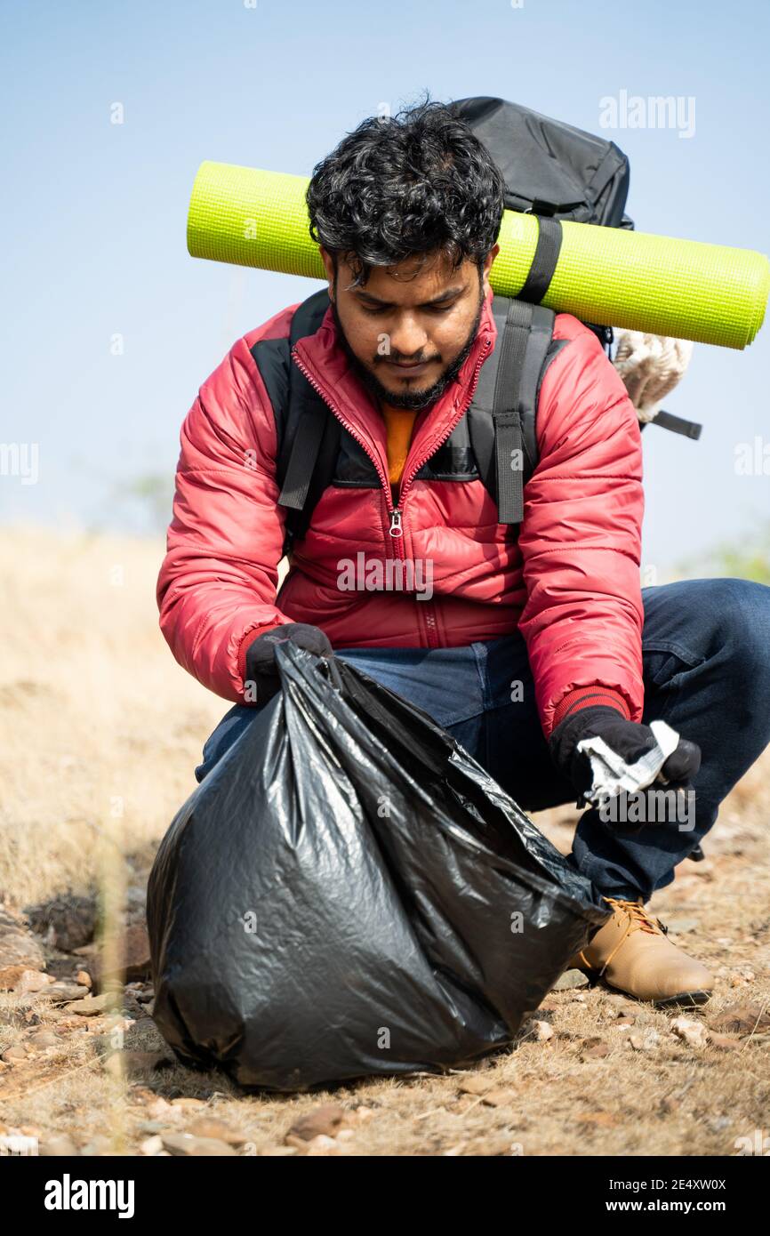 Young traveller collecting garbage or litter while hiking on mountain ...