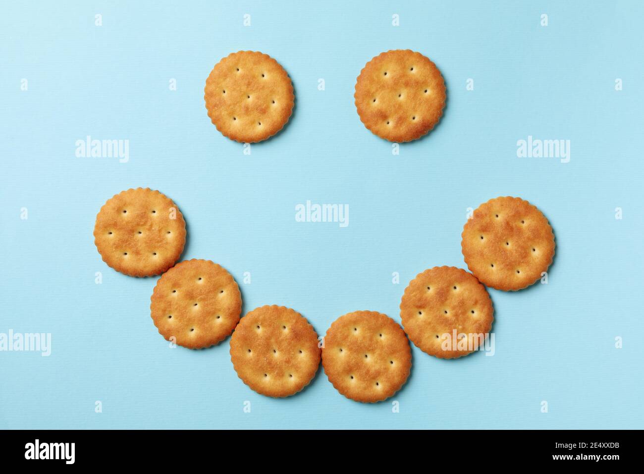 Smile face made of cracker biscuits on blue background Stock Photo - Alamy